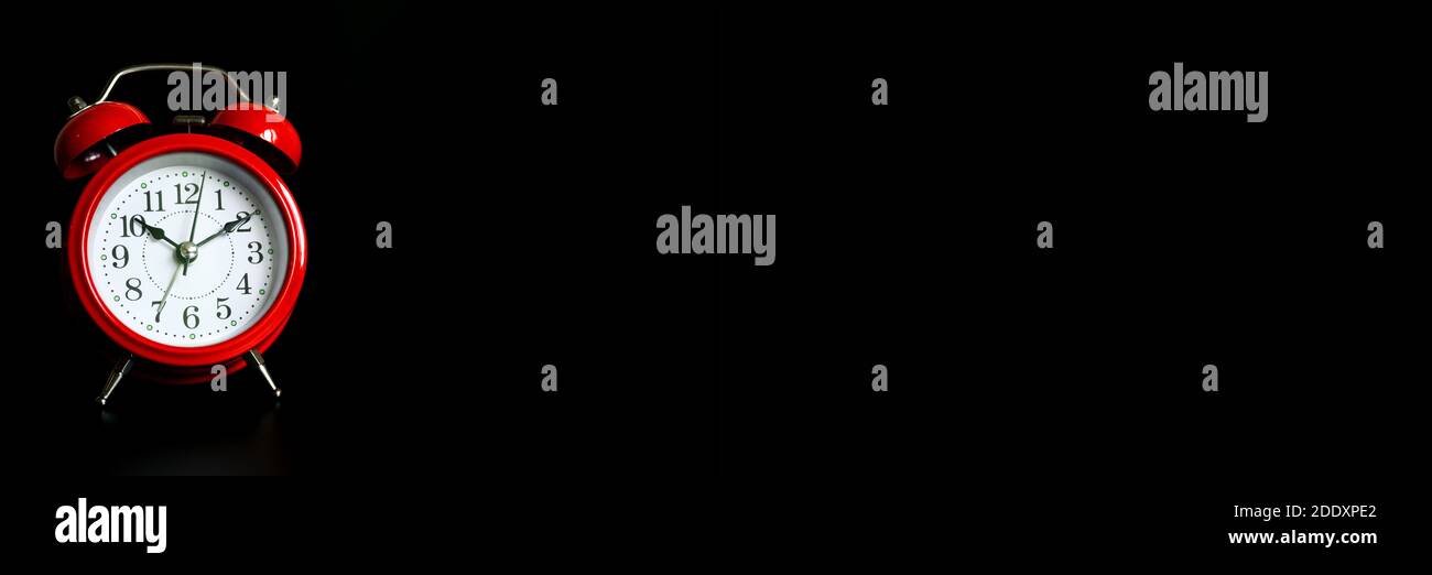 red round analog alarm clock isolated on black background. time 10:10 ...