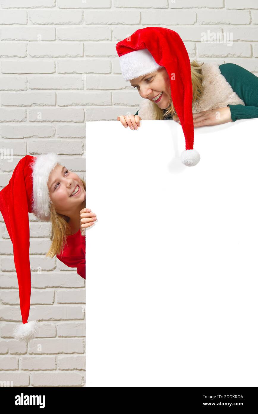 Mother and daughter peeking from behind blank sign billboard assign ...