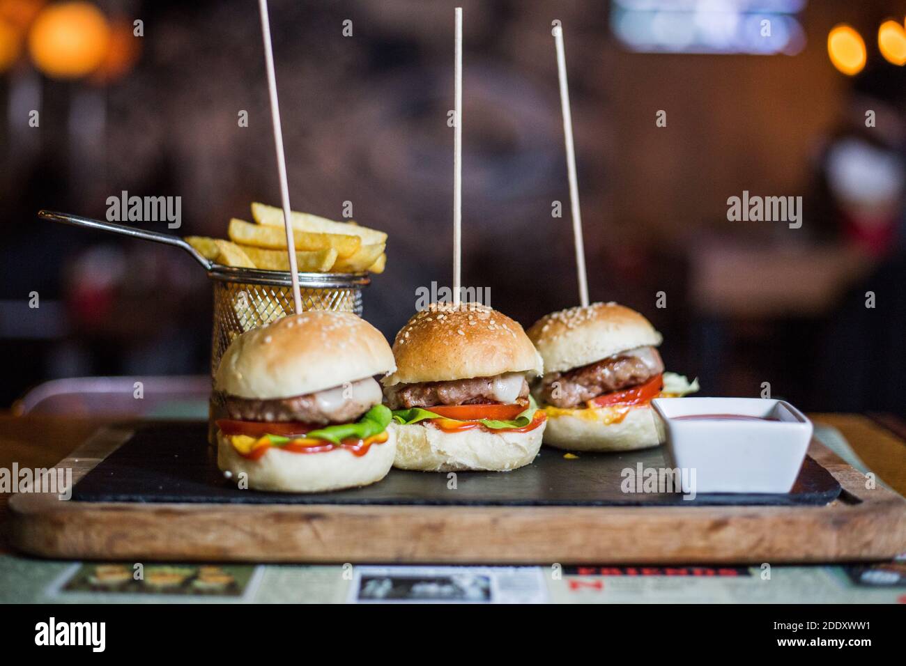 A closeup shot of three mini burgers with french fries and sauce on a ...