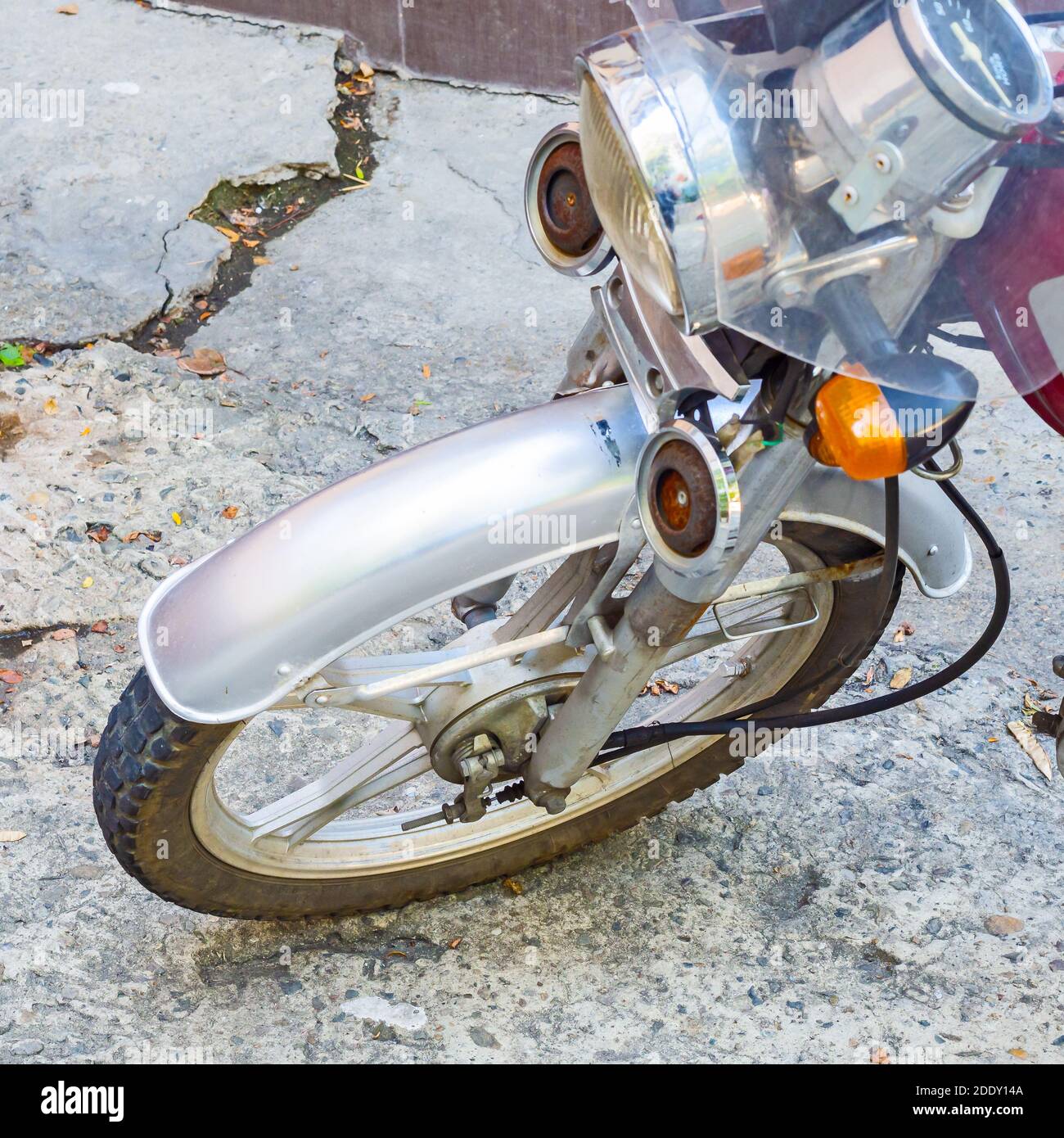 Fragment of a motorcycle with front wheel wires and headlights standing ...