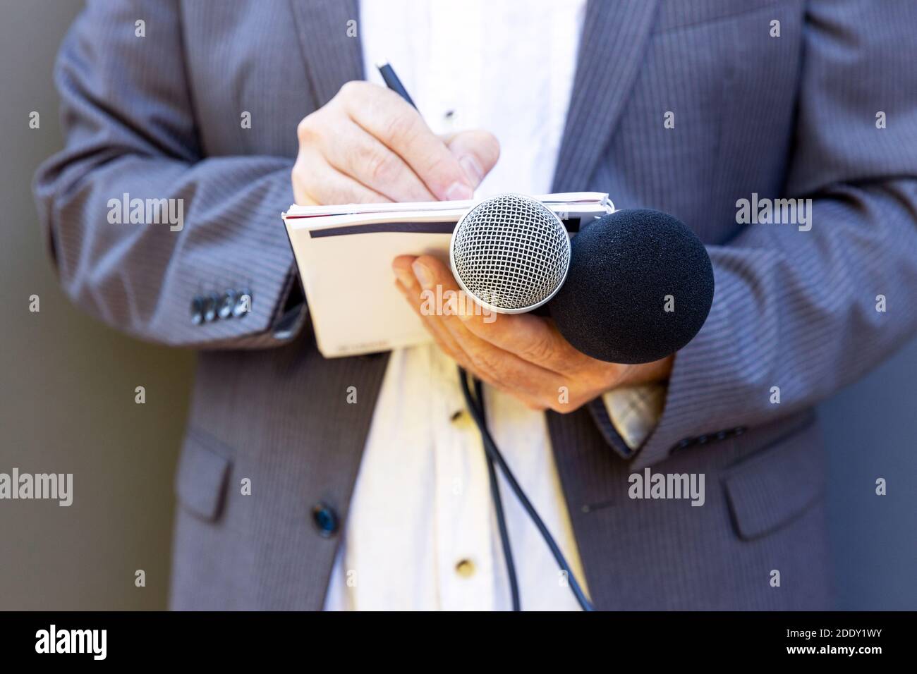 Journalist at news conference or media event, holding microphone ...
