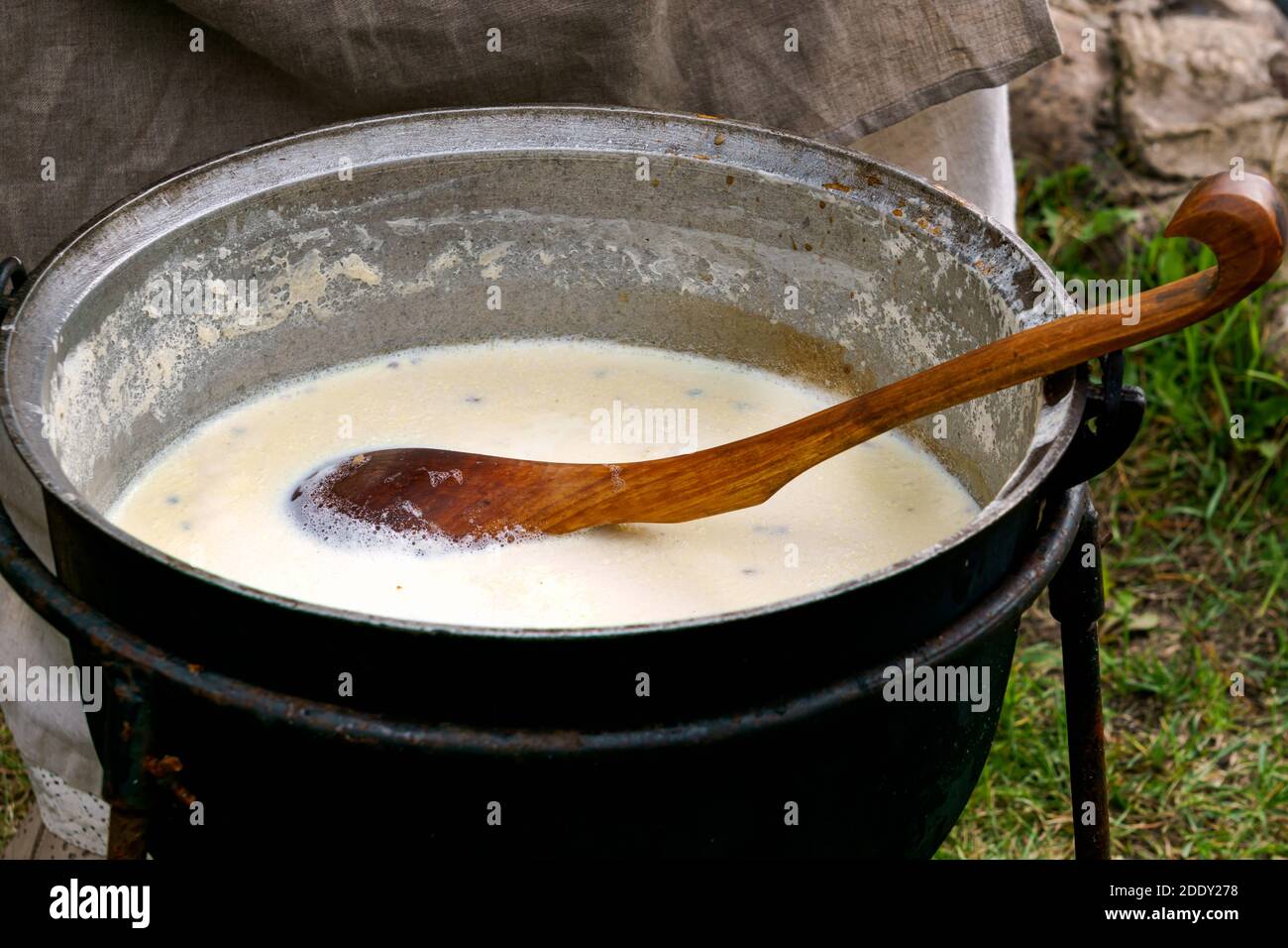 Homemade cheese production in a large cauldron over a fire Stock Photo ...