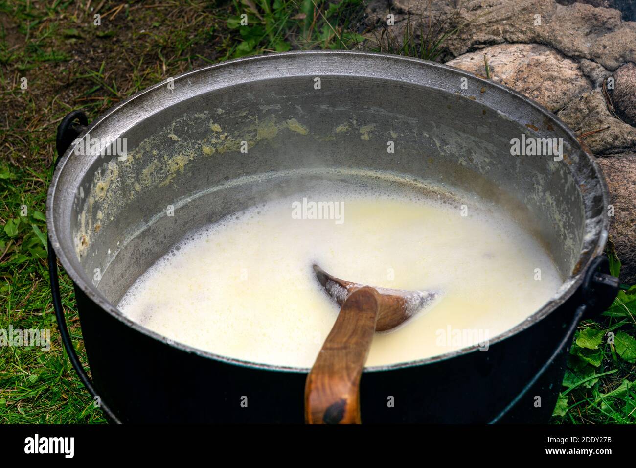 Homemade cheese production in a large cauldron over a fire Stock Photo ...
