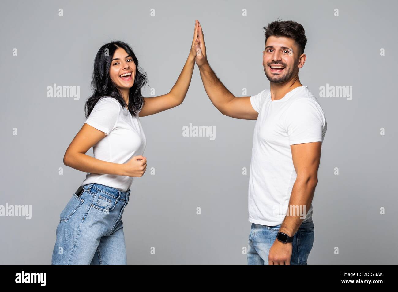 Portrait of a beautiful young couple standing and giving high five ...