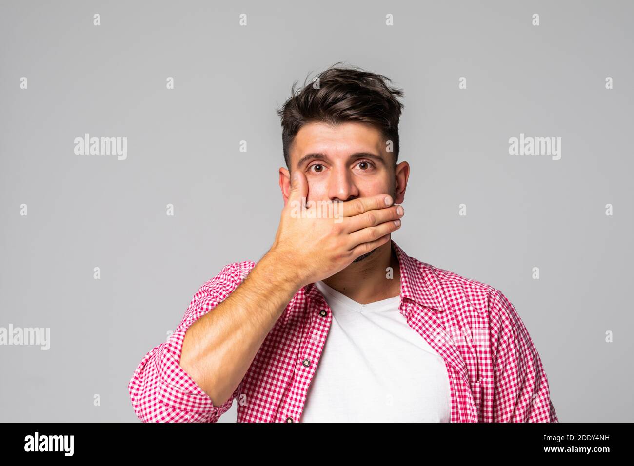Surprised young man covering mouth with hand. Embarrassed handsome guy ...