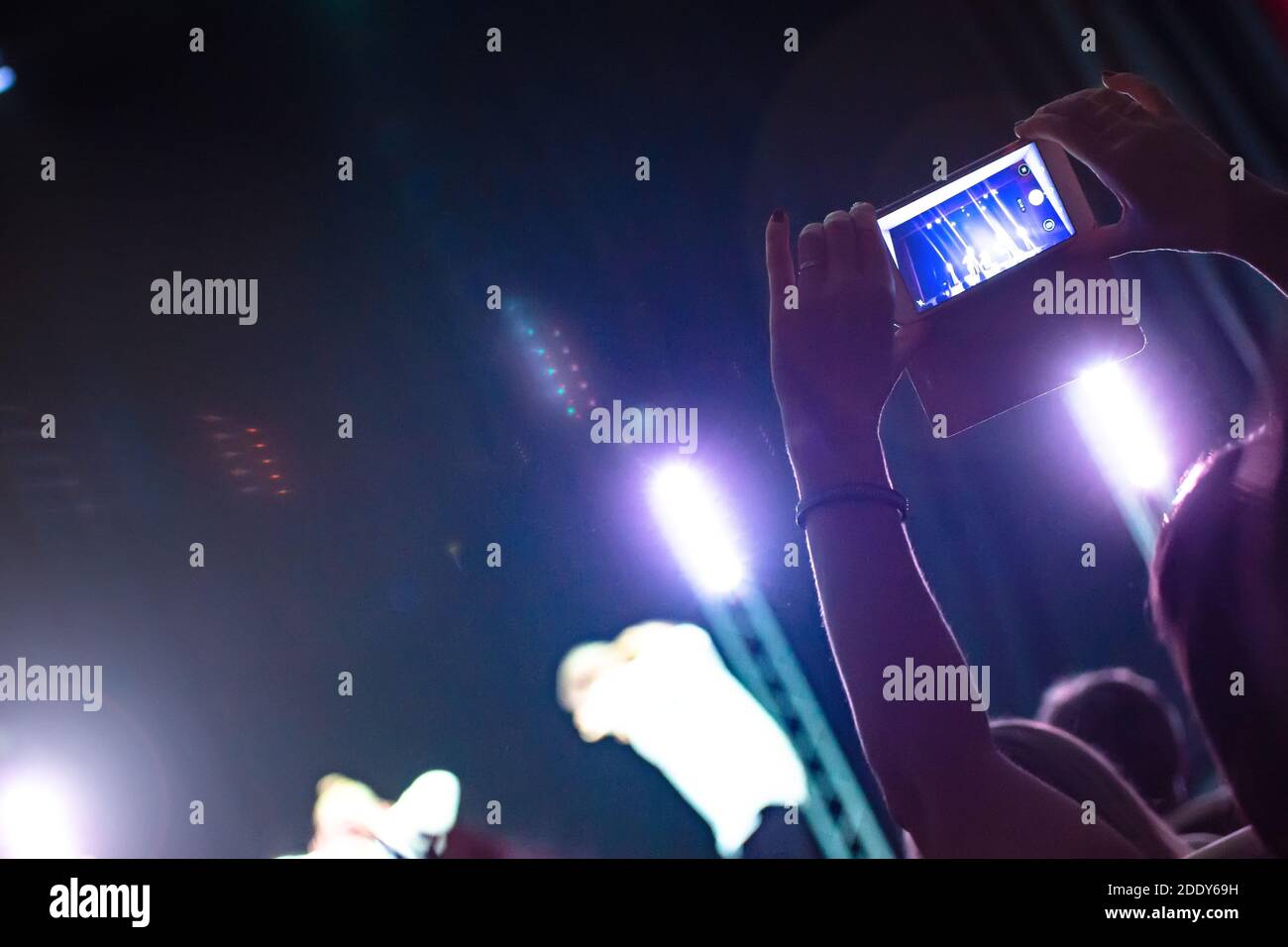 A man from a concert hall shoots a stage performance on a smartphone ...