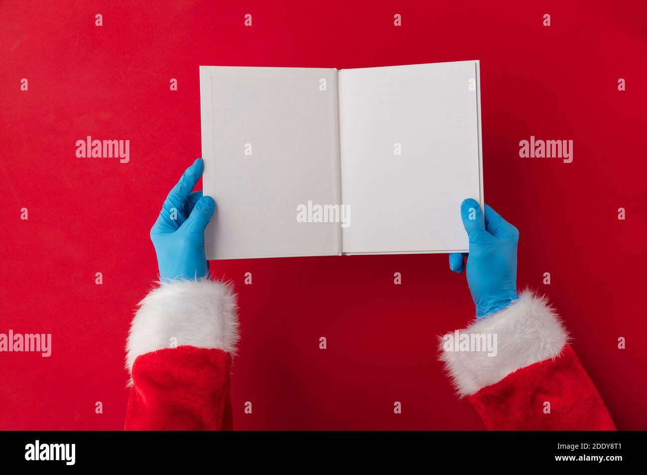 Santa hands wearing blue PPE protective gloves holding a blank book ...