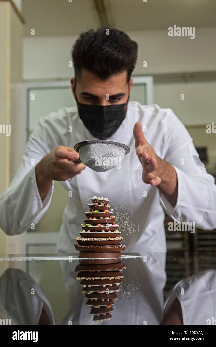 Pastry chef with a mask finishing a chocolate Christmas tree Stock ...