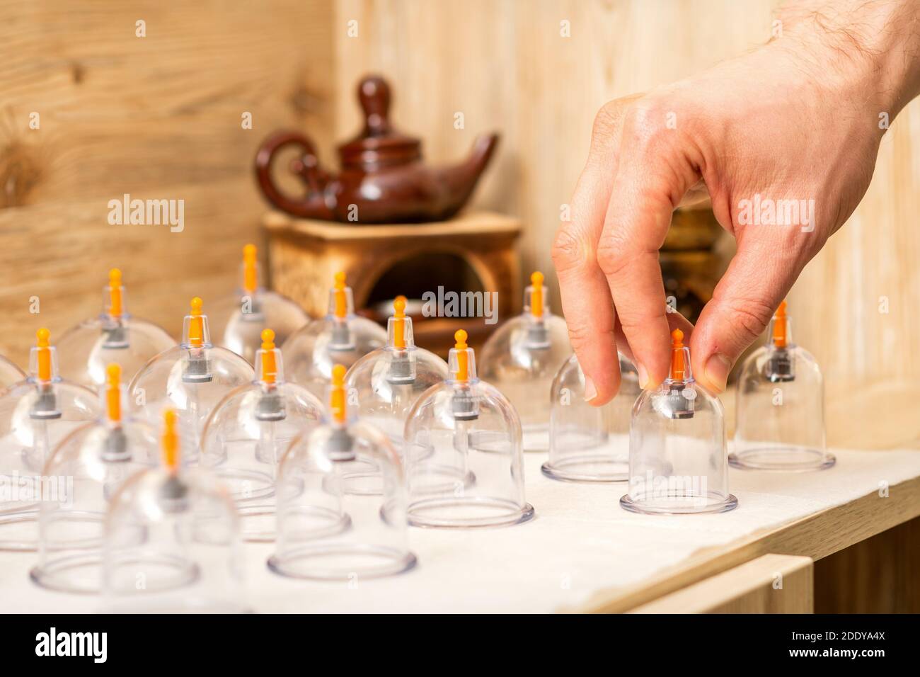 Hand of massage therapist takes vacuum glass jars from a table in a spa ...