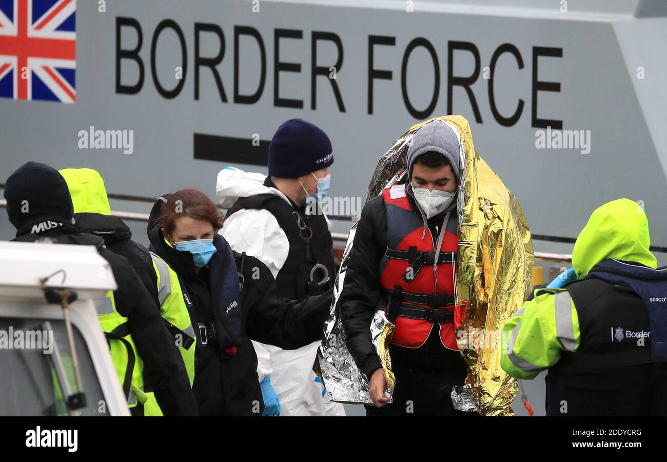 A man is helped by a Border Force officer as a group of people thought ...