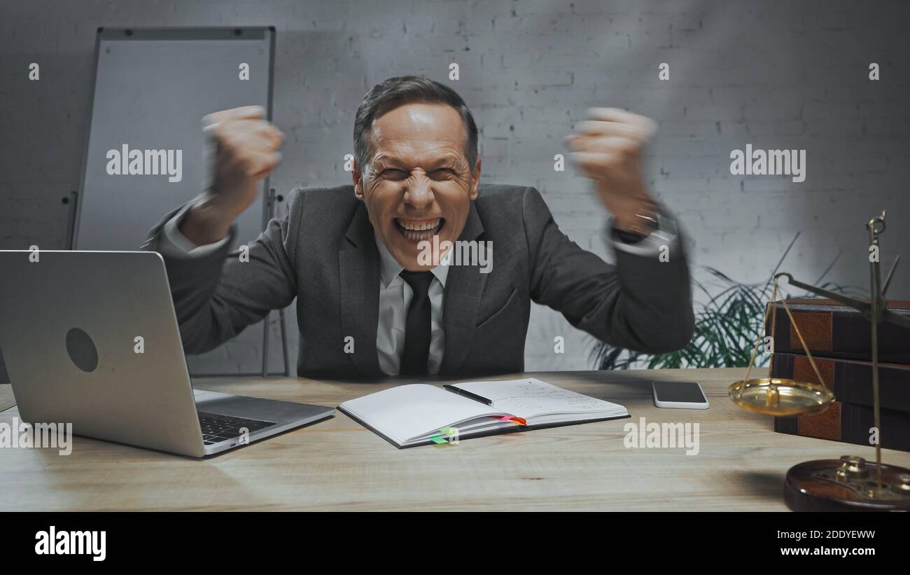 Angry insurance agent showing fists near devices, notebook and scales ...