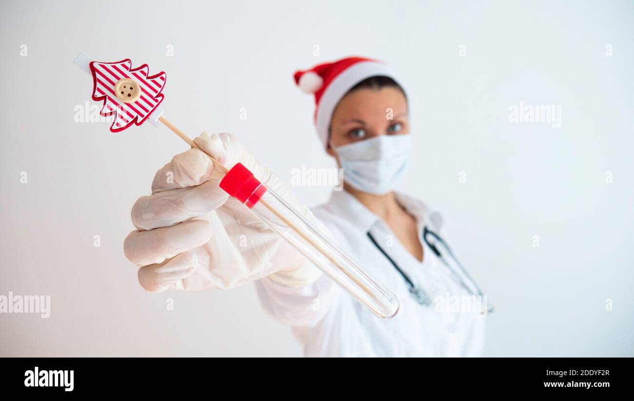 Female pediatrician with a Santa hat is holding medical swab Christmas ...