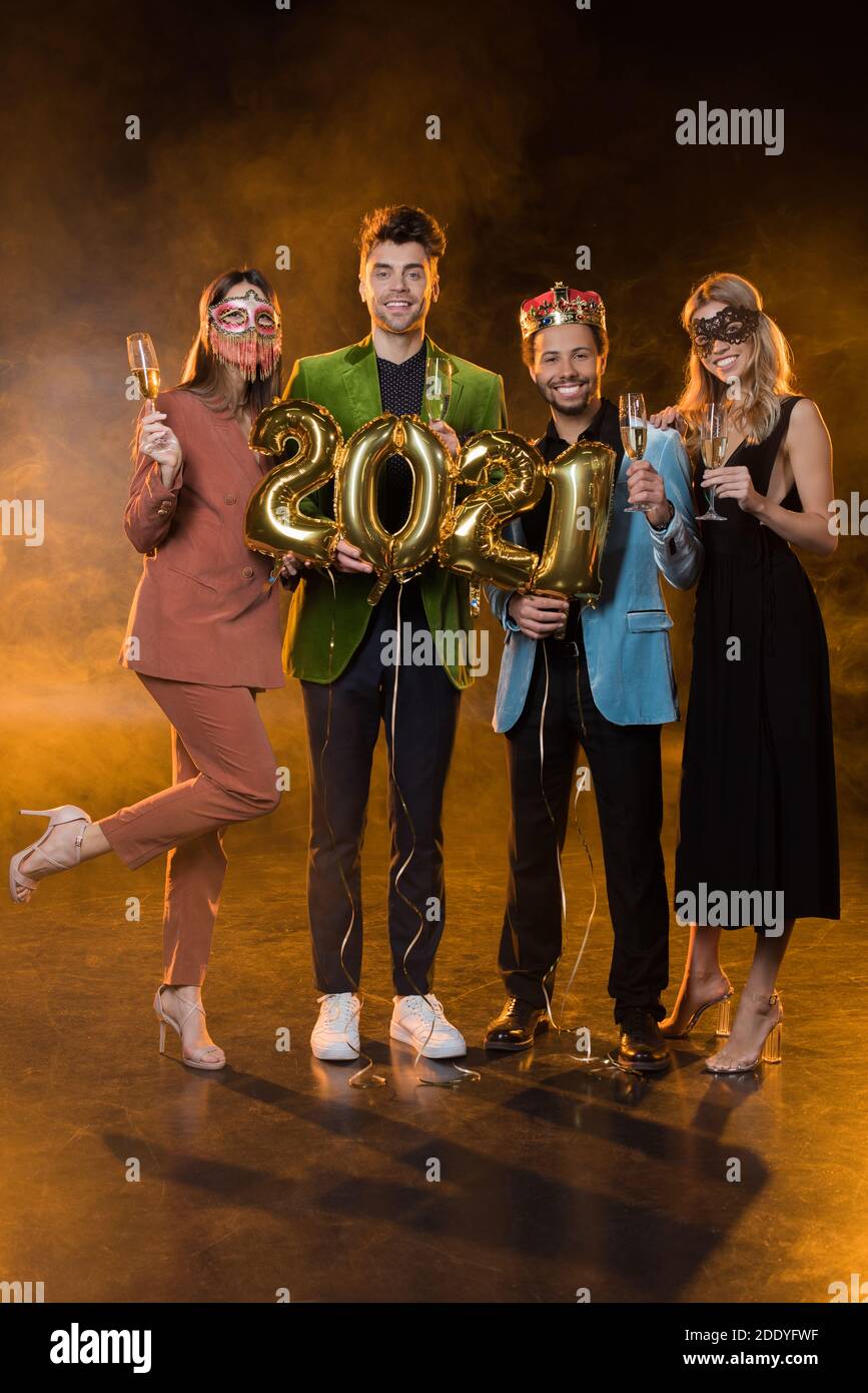 full length of happy multicultural men holding balloons with 2021 ...