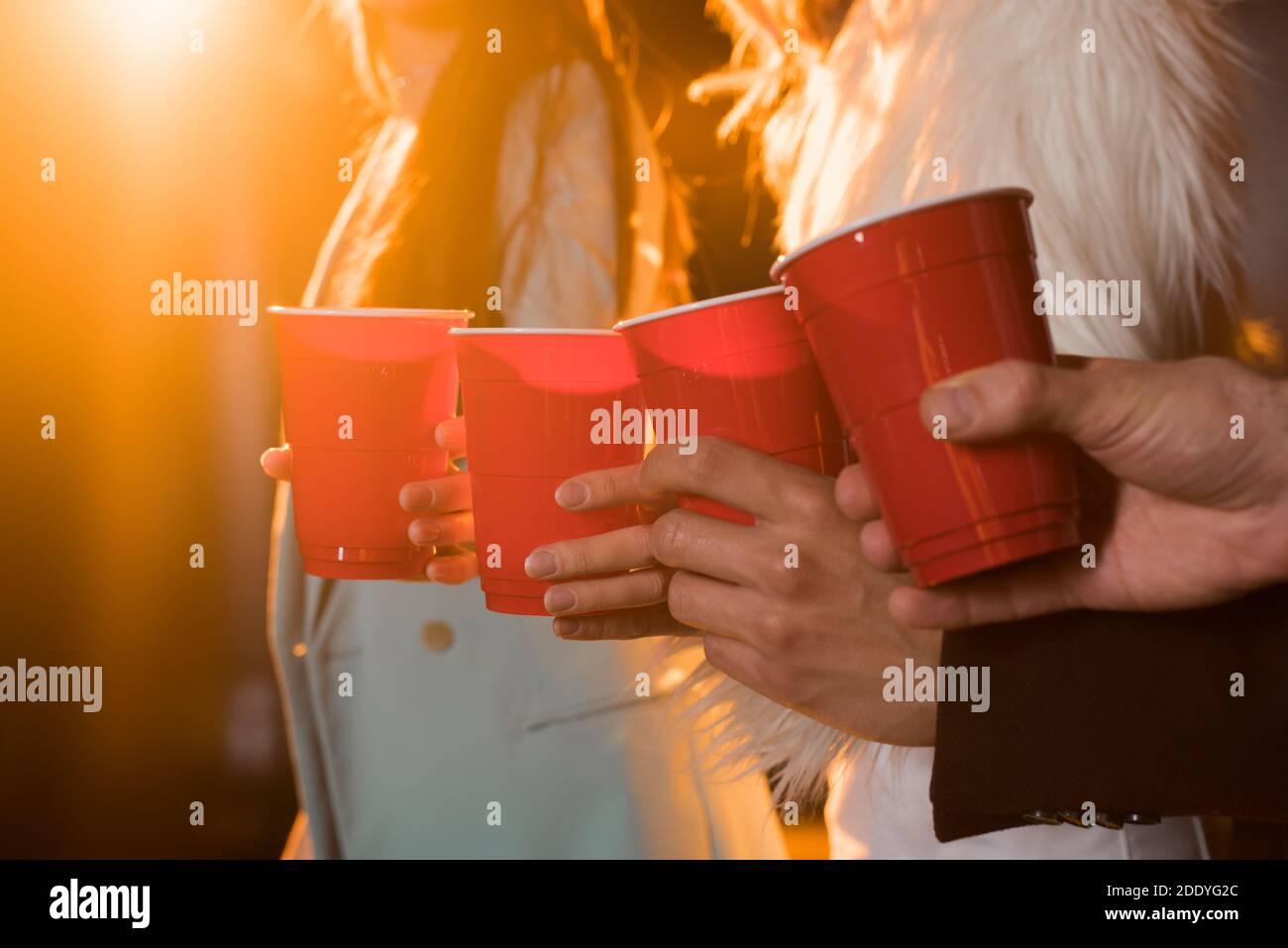 cropped view of friends toasting plastic cups on black Stock Photo - Alamy