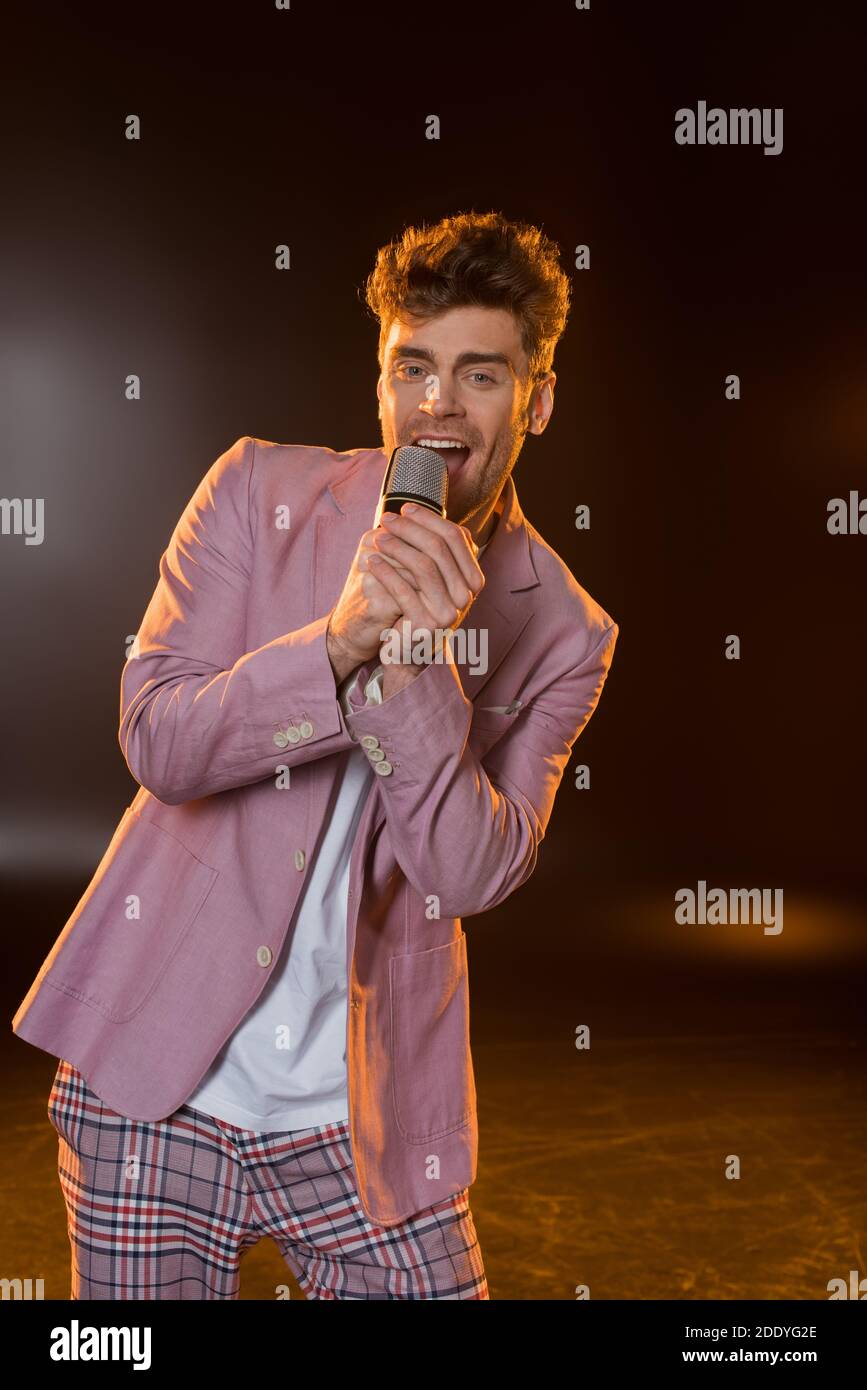 happy man singing while holding microphone on black Stock Photo - Alamy