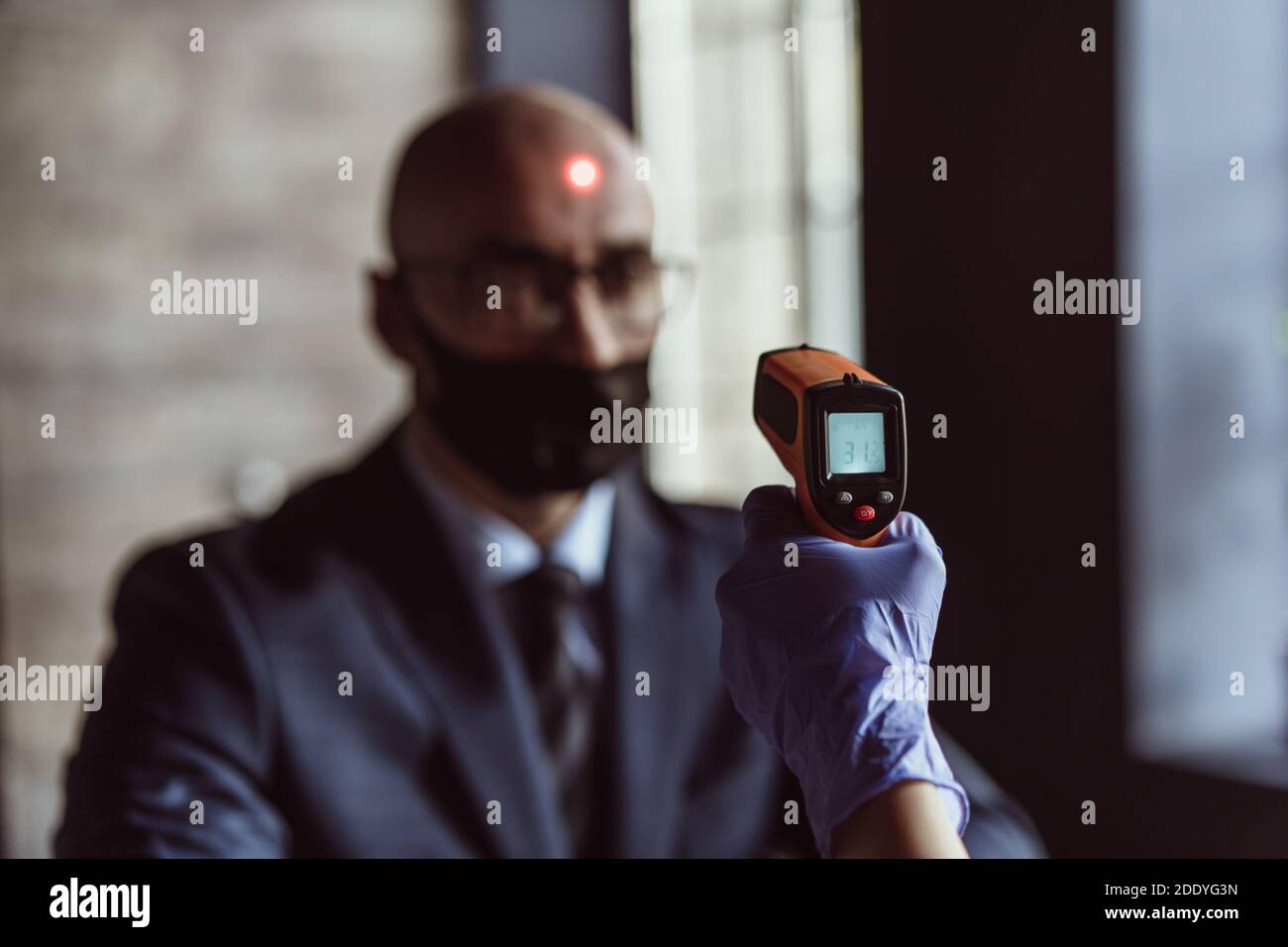 Health officer checking temperature of a businessman in the entrance of ...