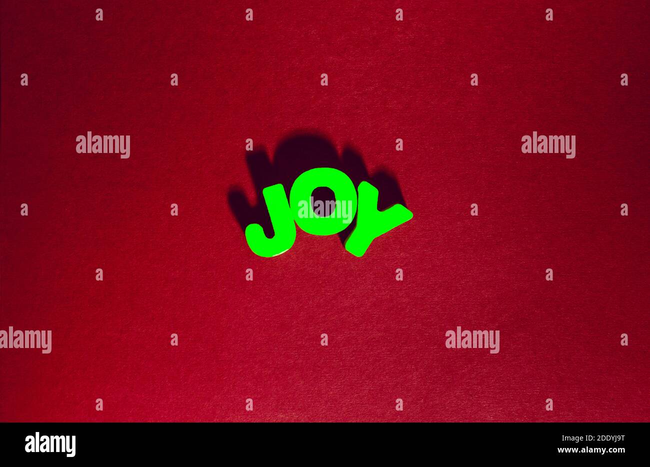 Bright green text word Joy by wooden letters at red craft paper ...