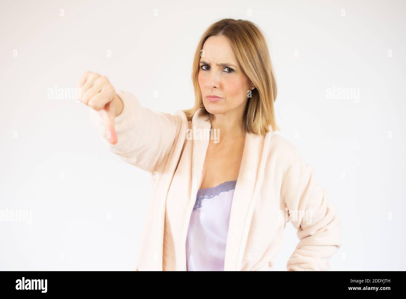 Portrait of beautiful young woman in nightgown pointing down over white ...