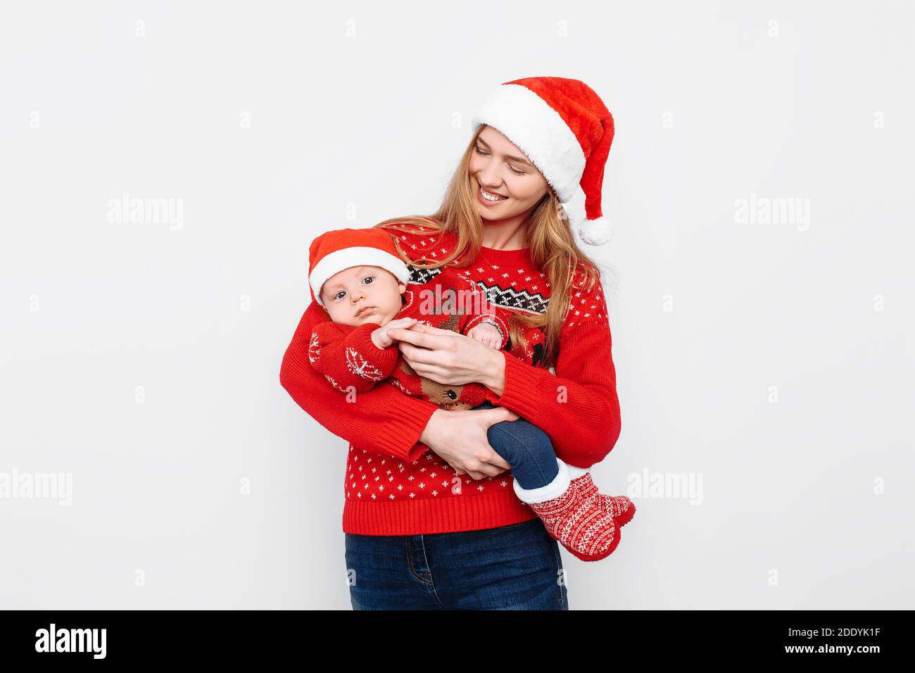 Happy young mother in santa hat with charming little baby in santa ...