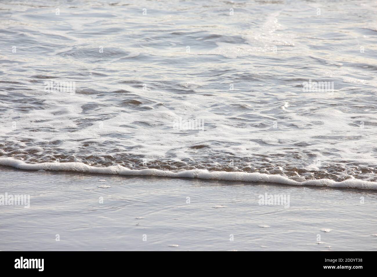A close up photograph of water coming in on a beach Stock Photo - Alamy