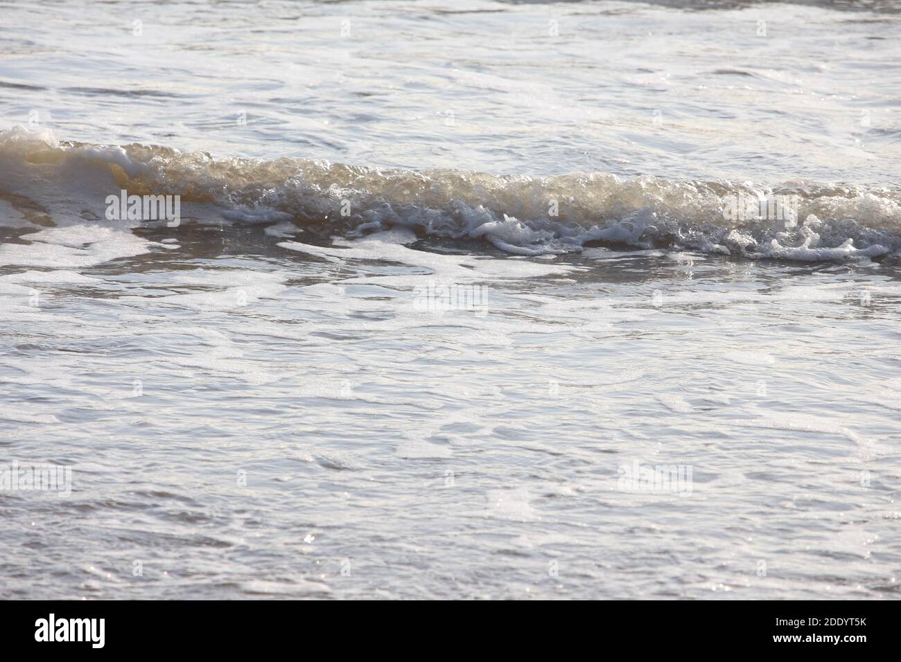 A close up photograph of water coming in on a beach Stock Photo - Alamy