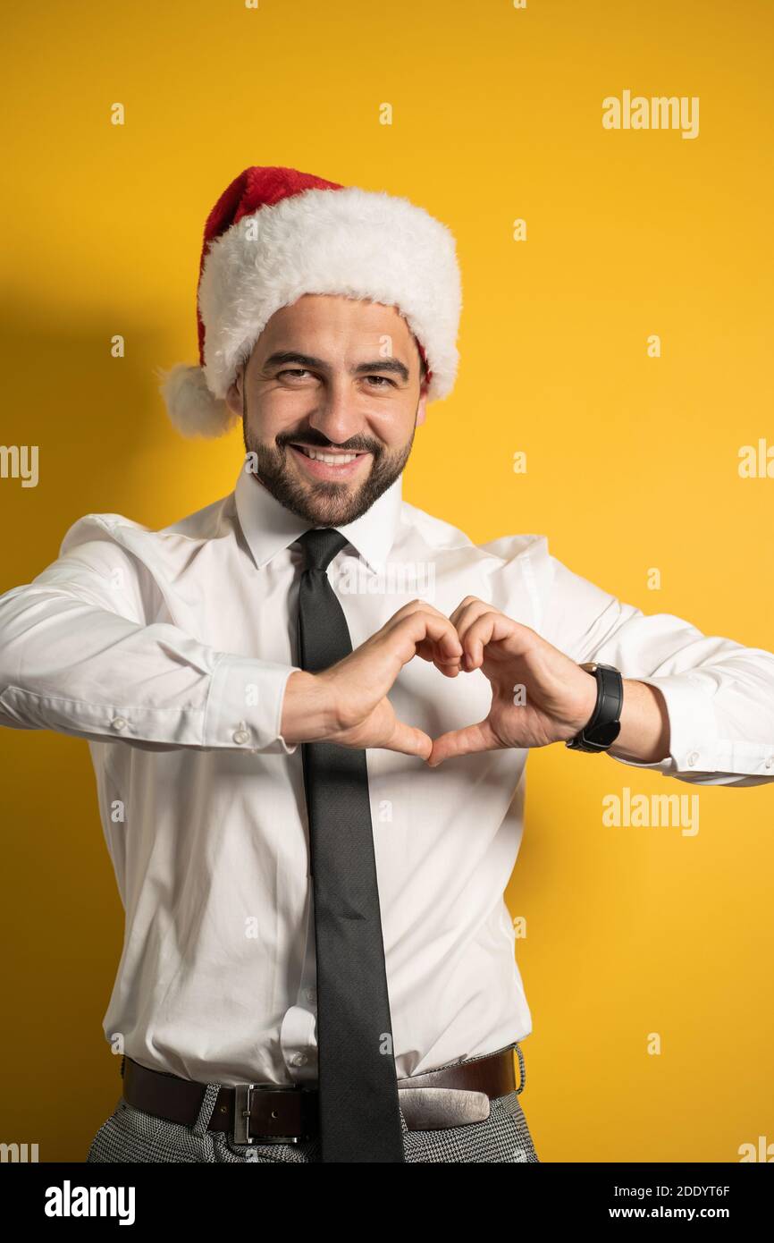 Handsome smiling bearded man in Santa hat showing hear gesture isolated ...
