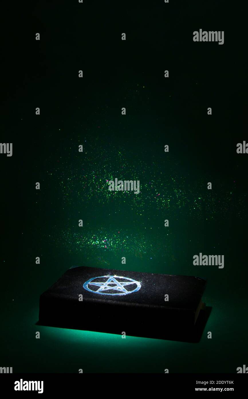 Black magic book on the dark green background Stock Photo - Alamy
