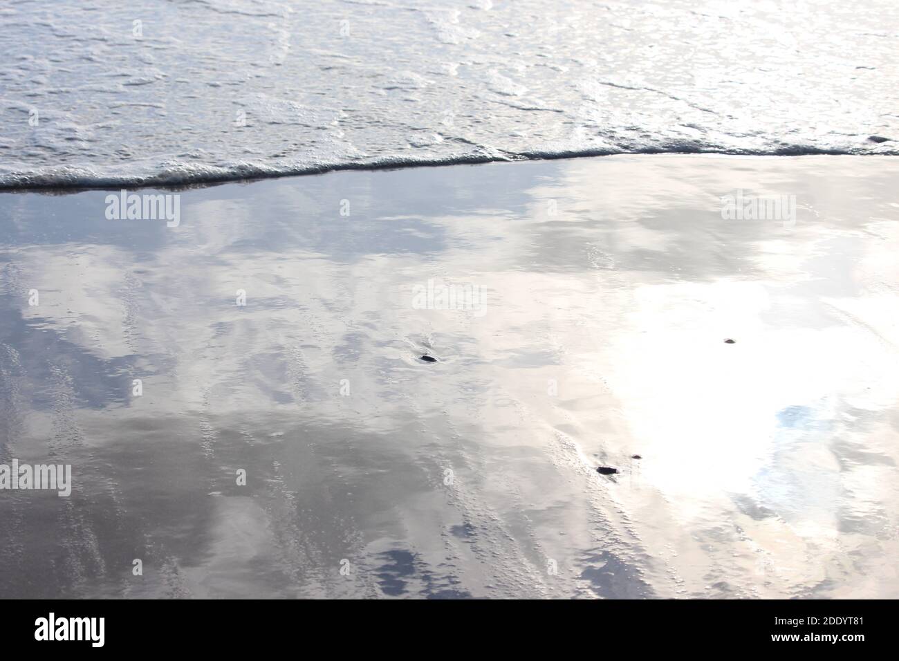 A close up photograph of water coming in on a beach Stock Photo - Alamy