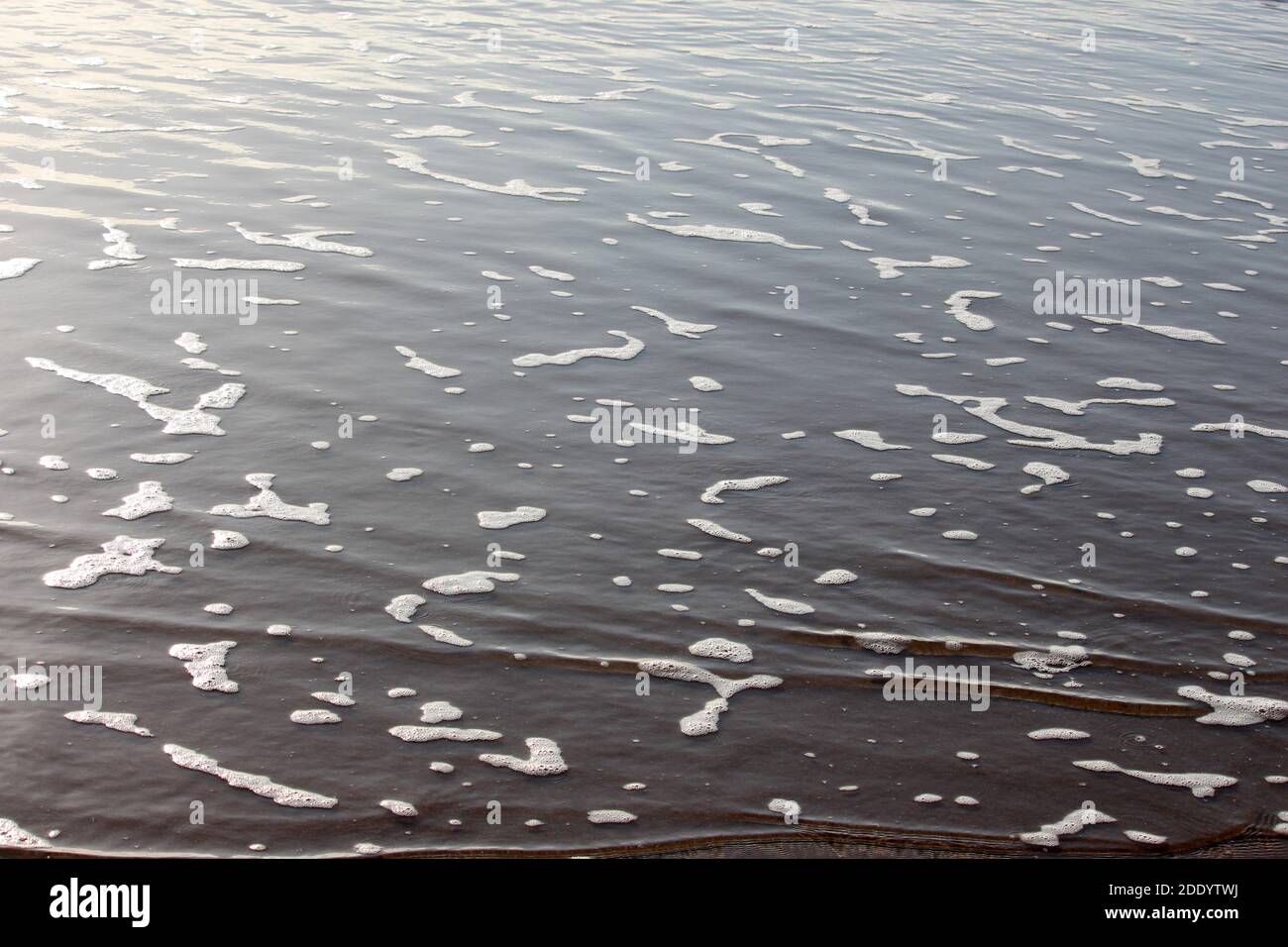 A close up photograph of water coming in on a beach Stock Photo - Alamy