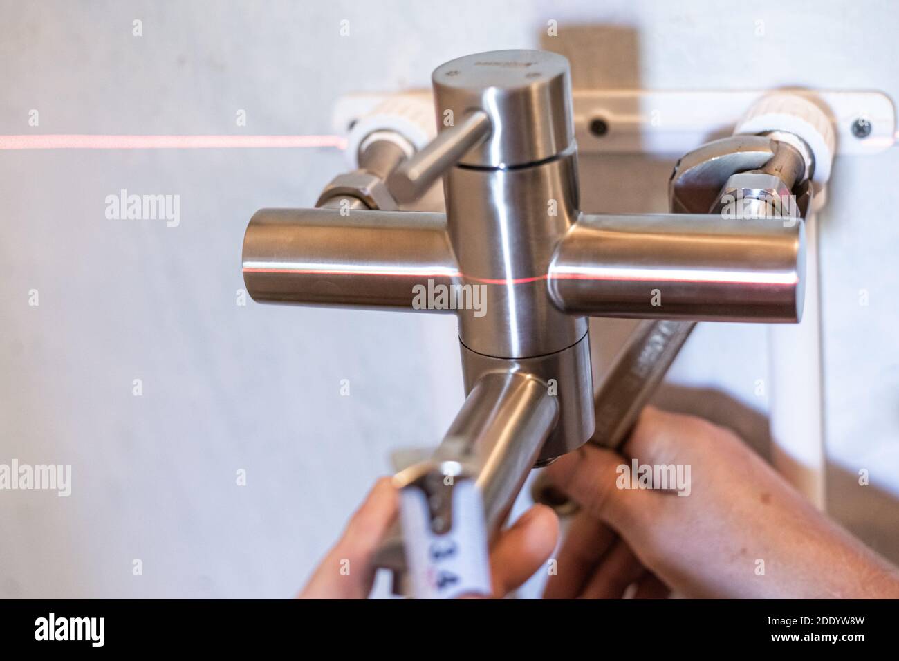 plumber assembles an iron faucet for tap water using a key and a laser ...