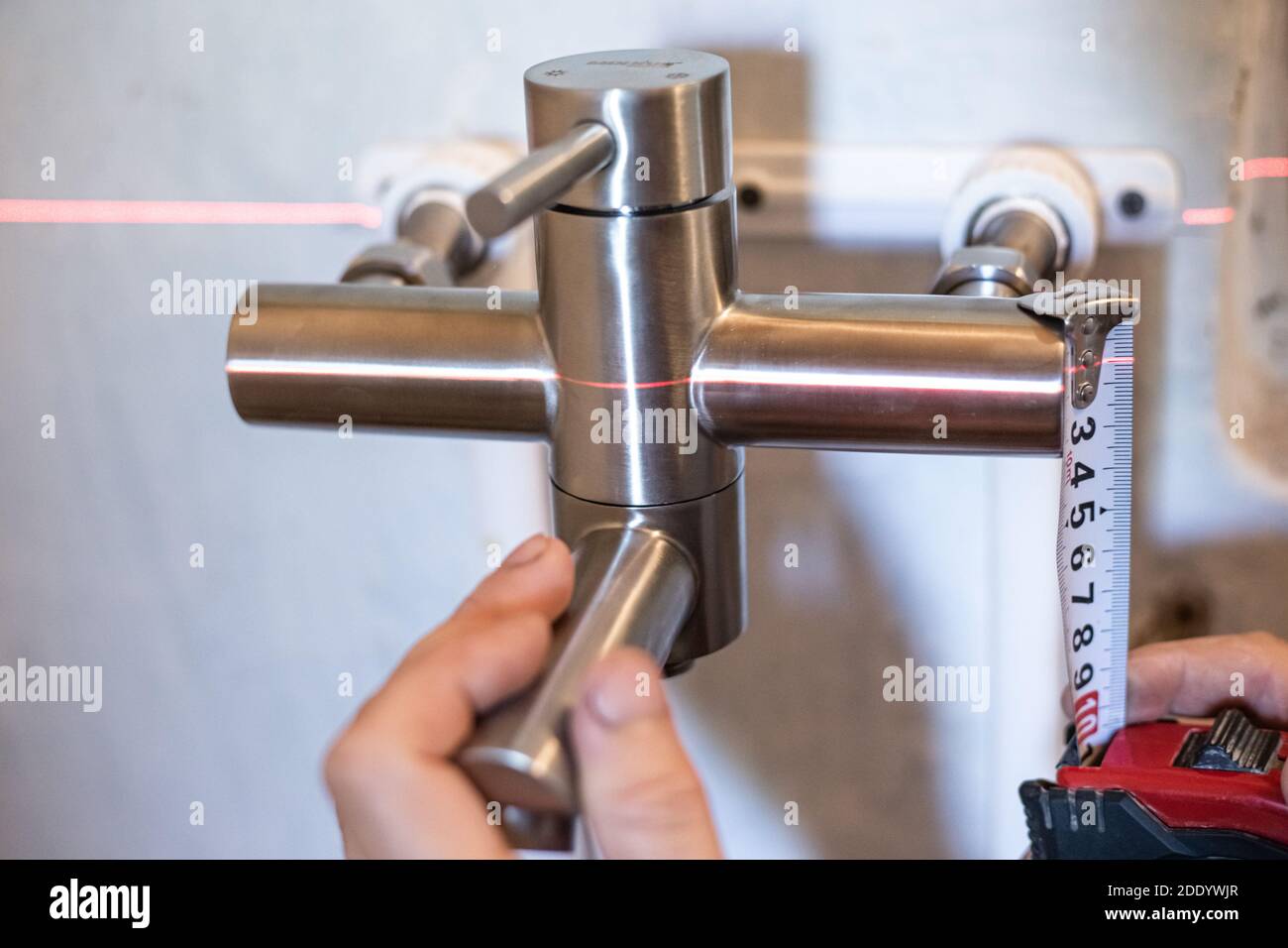 Sanhnik assembles an iron mixer for water supply, using a laser level ...