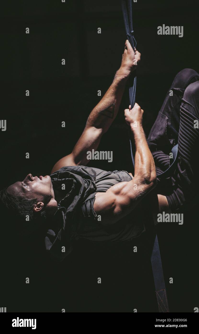 Athlete with a well-developed musculature lifts up his body on the rope ...