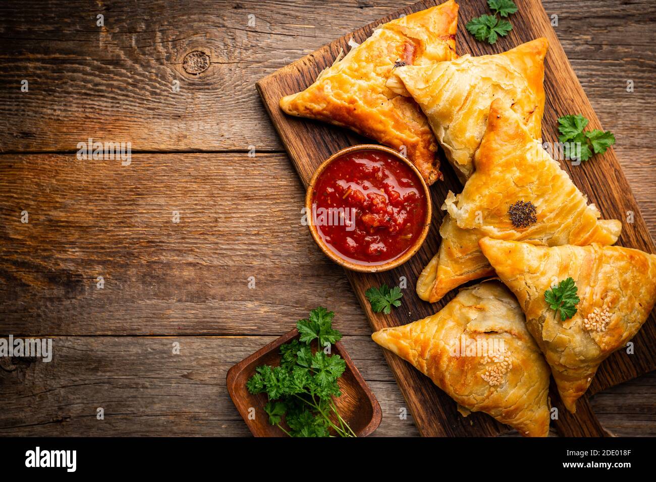 Samsa or samosas with meat and vegetables with tomato sauce on wooden ...