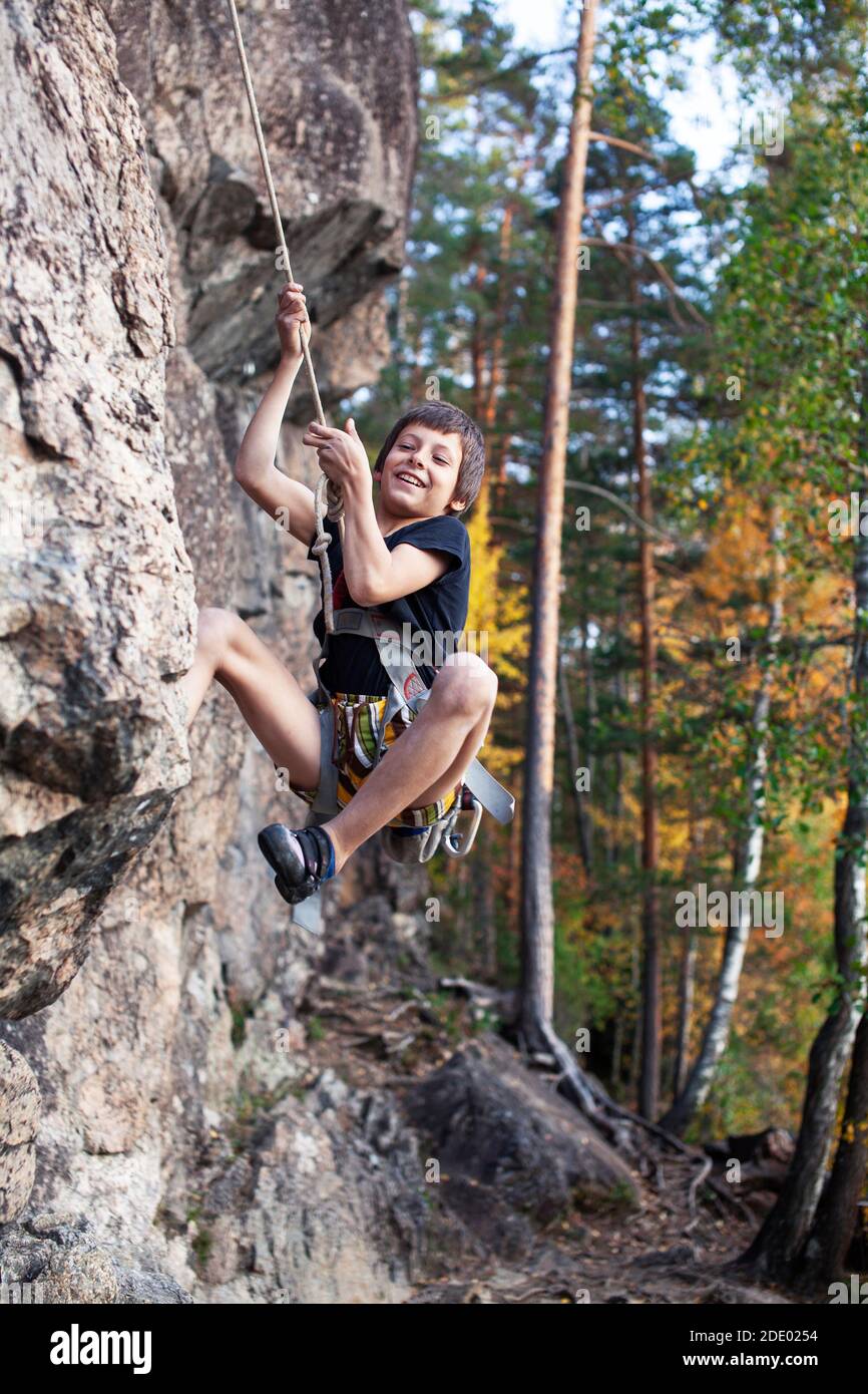 cute teen kid climbing on rock with insurance, lifestyle sport people ...