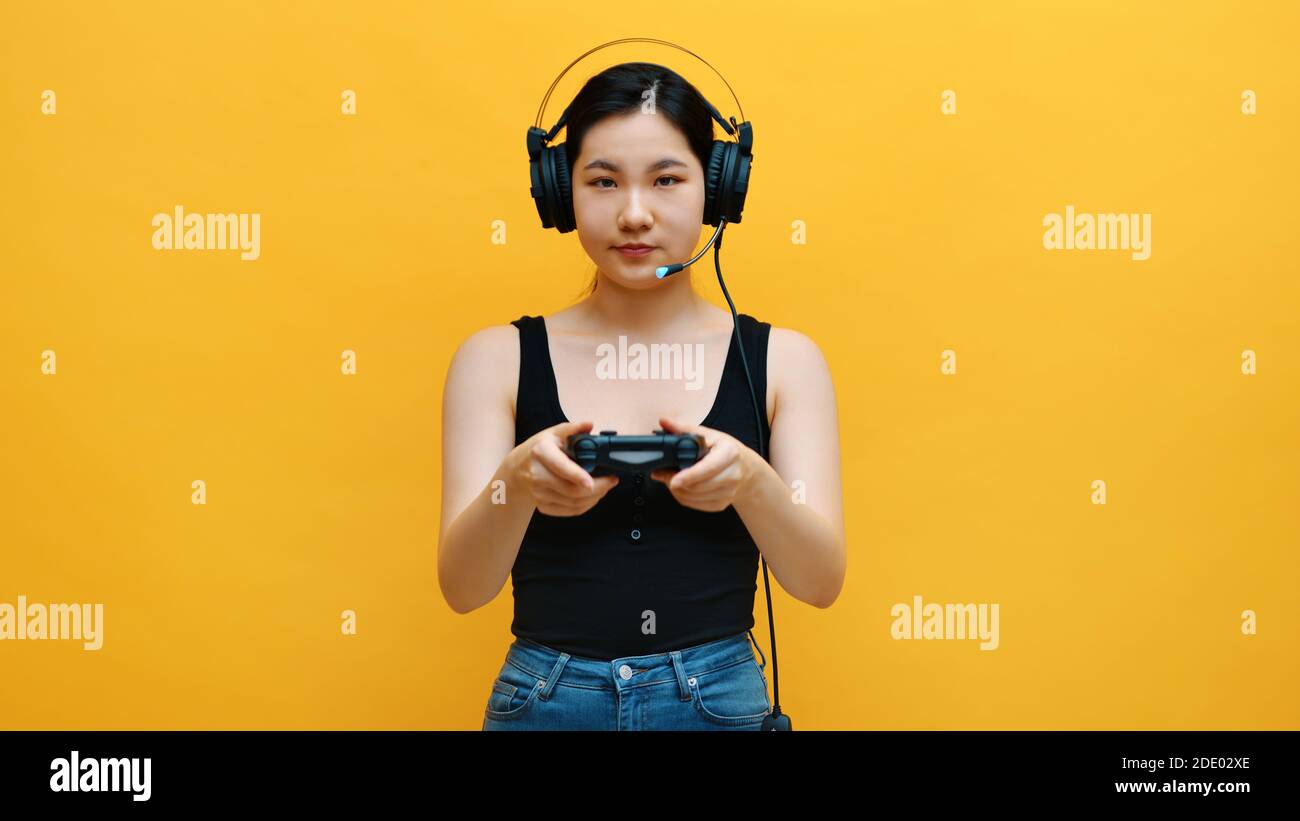 Focused young asian woman with headset and joystic controller playing ...