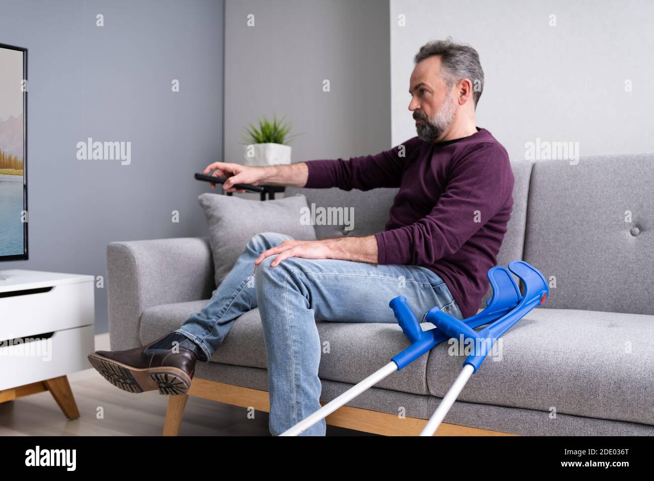 Injured Man With Broken Leg And Crutches Watching TV Stock Photo - Alamy