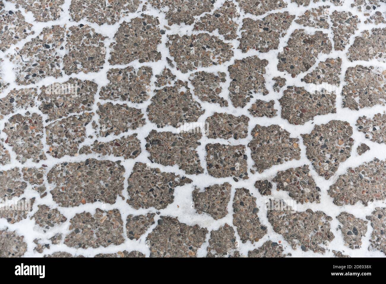 Cracks on the asphalt filled with snow. a Winter road texture ...