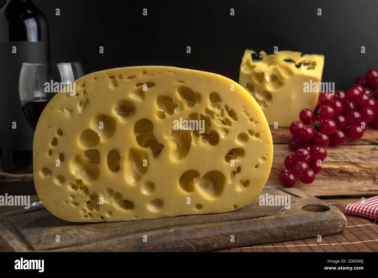 A closeup shot of a block of gourmet swiss cheese on a wooden board ...