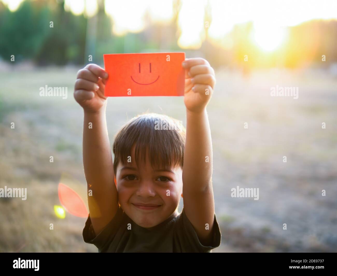 A kid is holding a paper with positive face on it, setting sun Stock ...