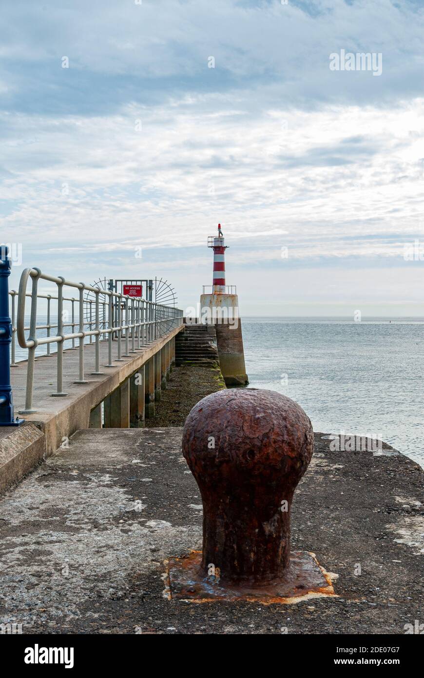 Rusty old mooring point on a jetty with a red and white striped ...