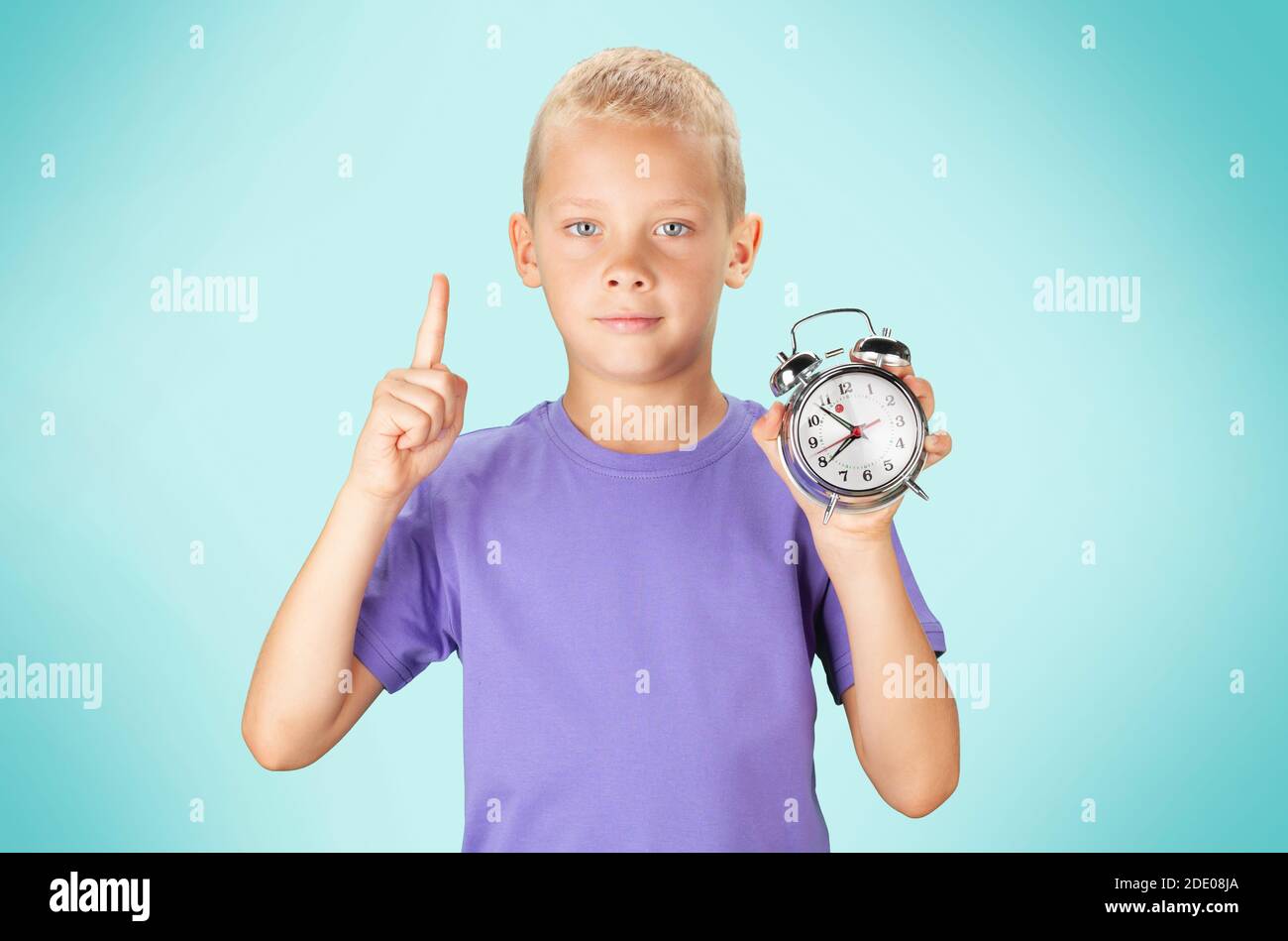 School boy showing alarm clock. Over color background Stock Photo - Alamy