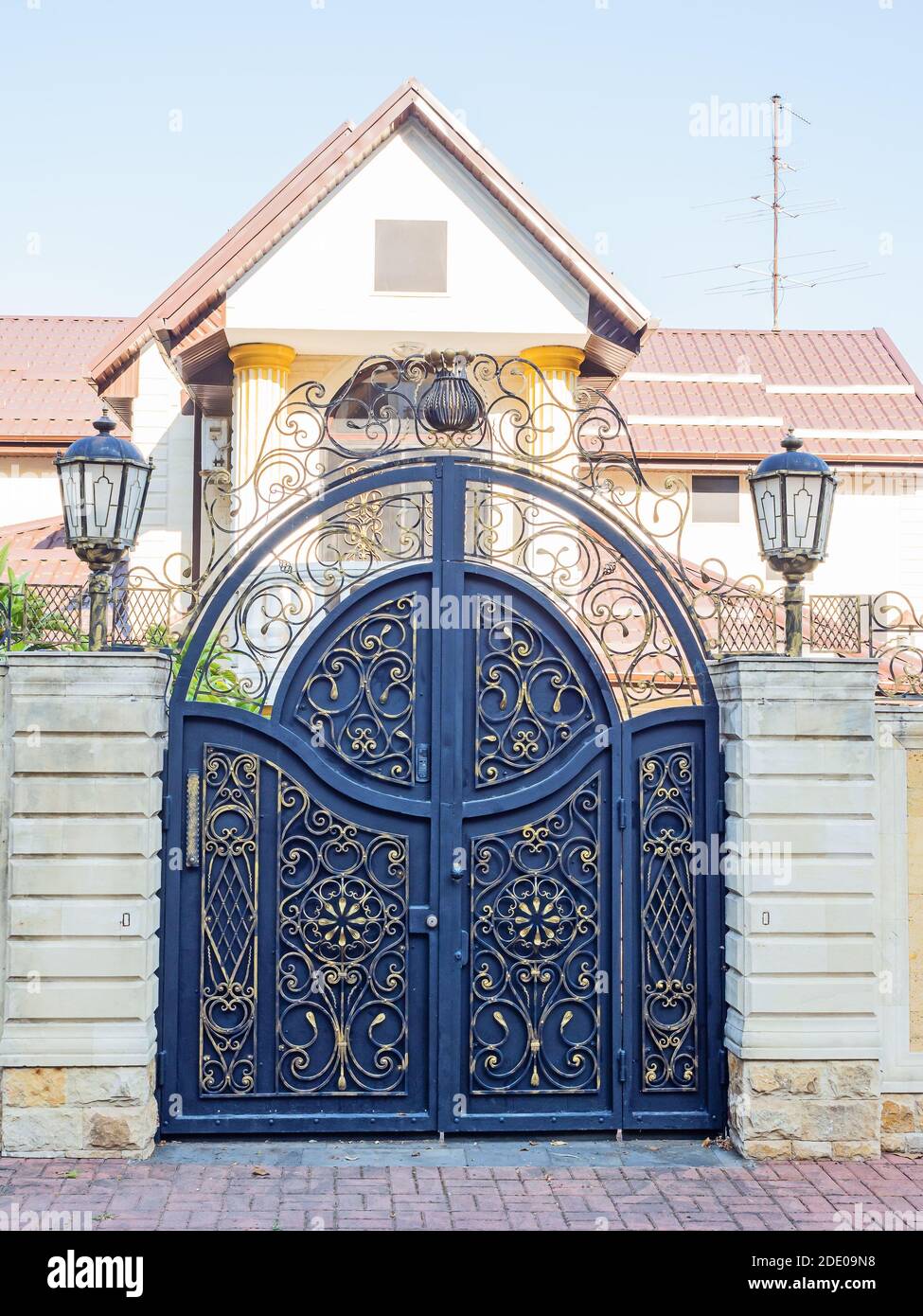 Rounded iron gates with a gilded wrought pattern and a fence enclosing ...
