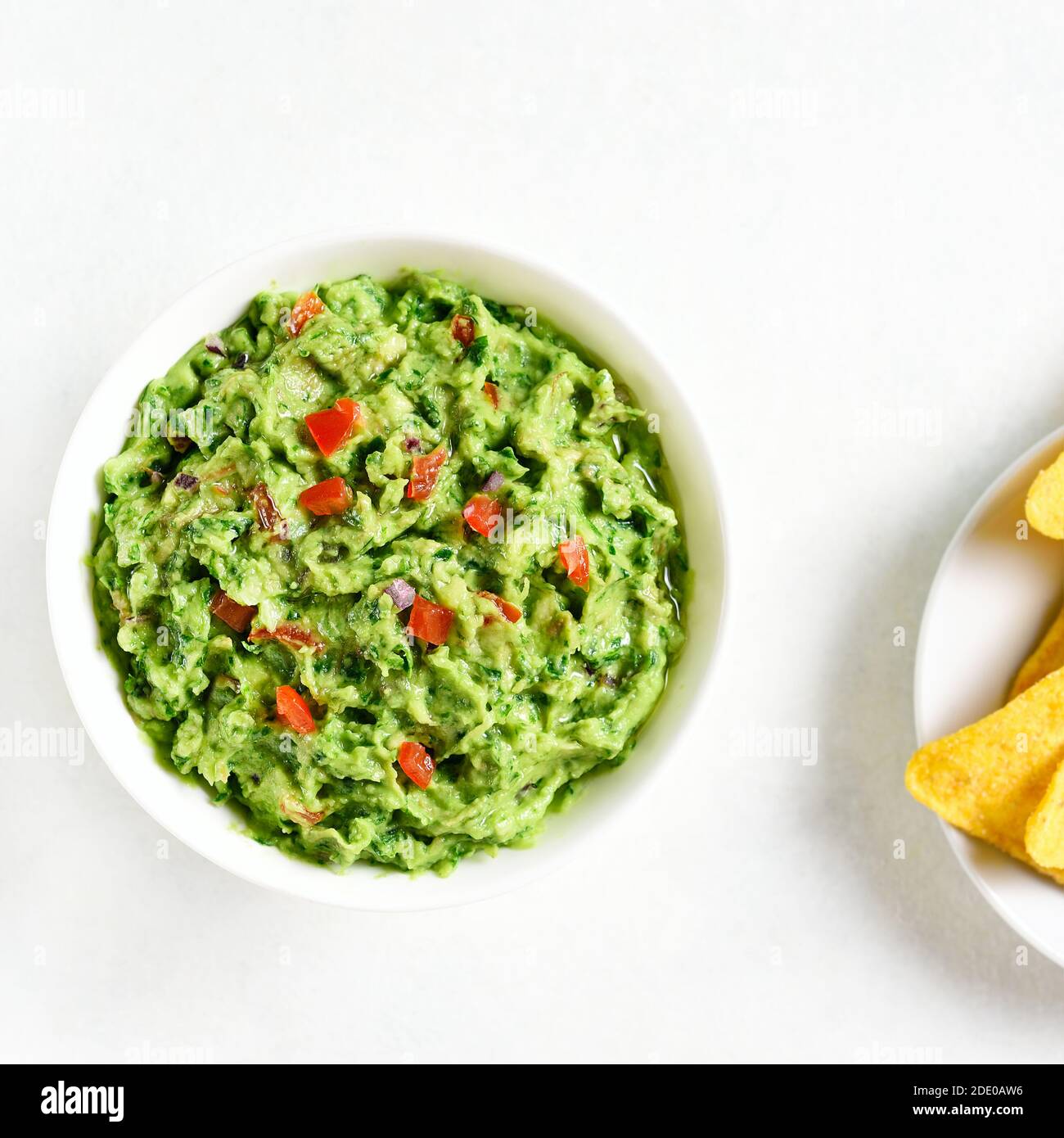 Guacamole dip in a bowl over white stone background. Healthy avocado ...