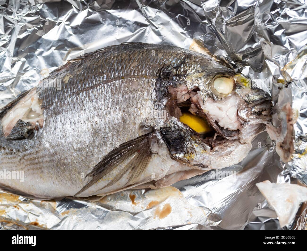 open cooked Orata fish stuffed by lemon baked in foil Stock Photo - Alamy