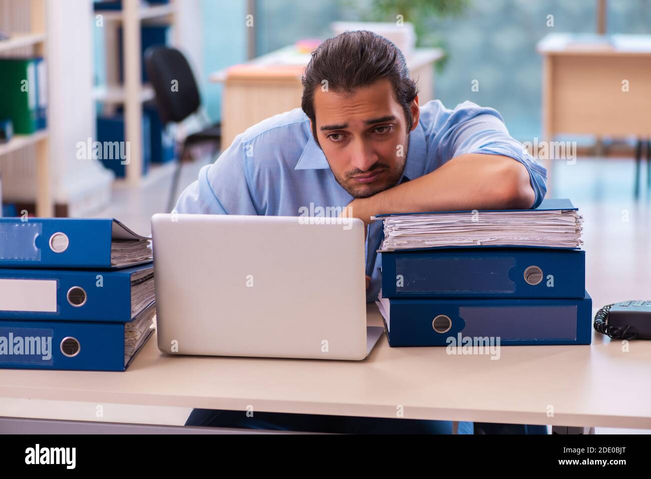 Young employee and too much work in the office Stock Photo - Alamy