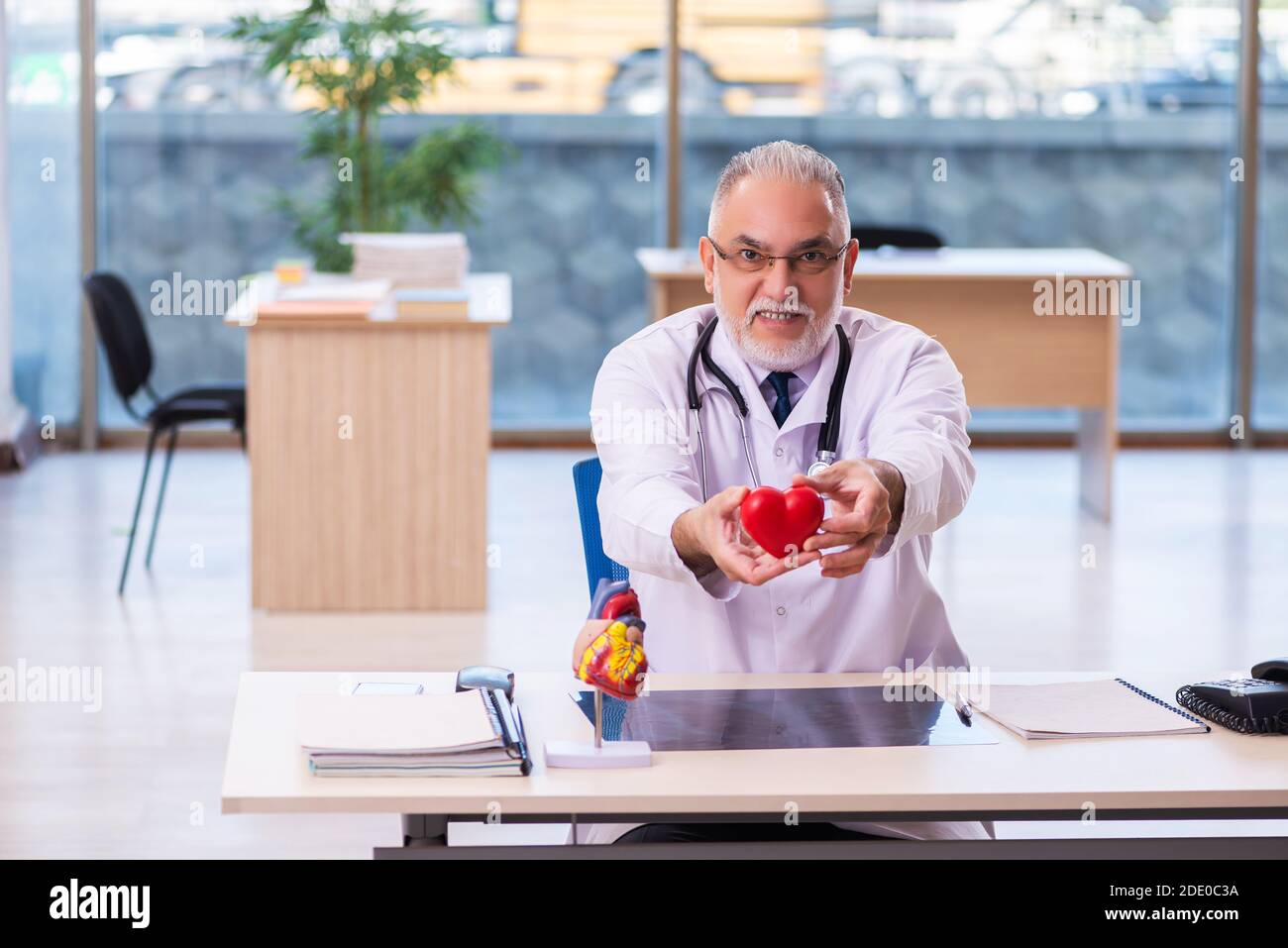 Old doctor cardiologist working in the clinic Stock Photo - Alamy