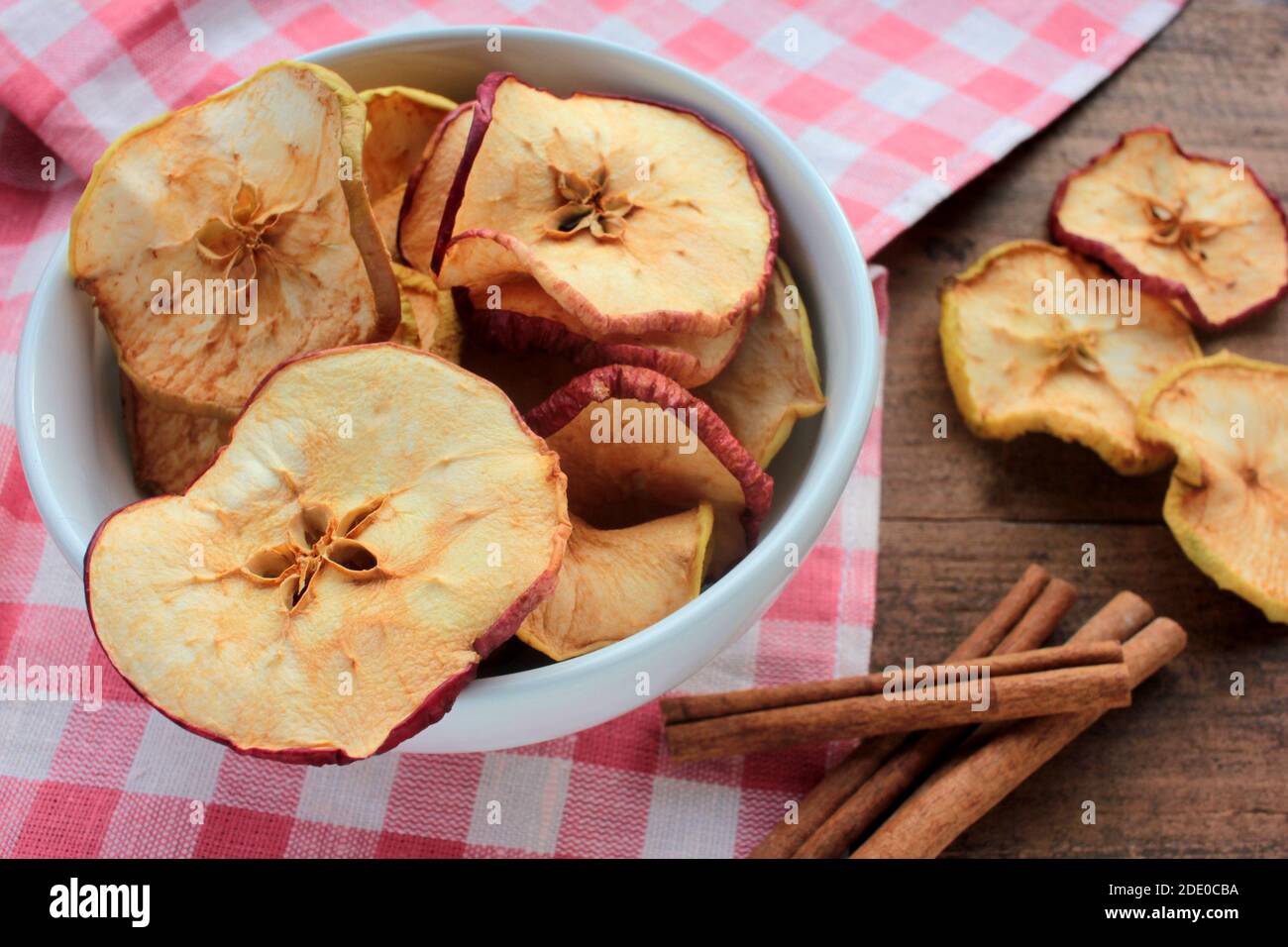 Dried fruits apples rings in a bowl, and cinnamon sticks on wooden ...