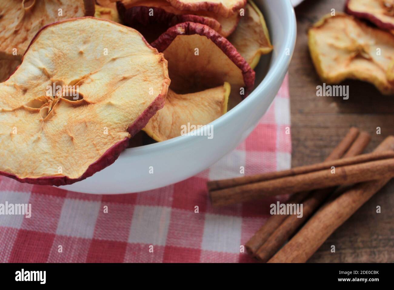 Dried fruits apples rings in a bowl, and cinnamon sticks on wooden ...