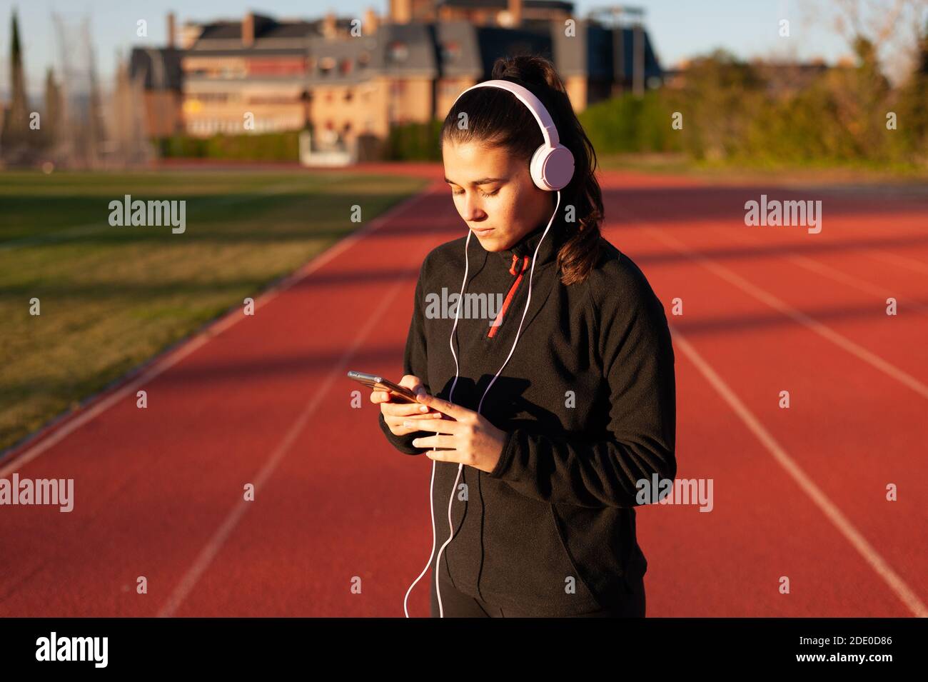 young woman athlete looks at the mobile with the headphones on on the ...