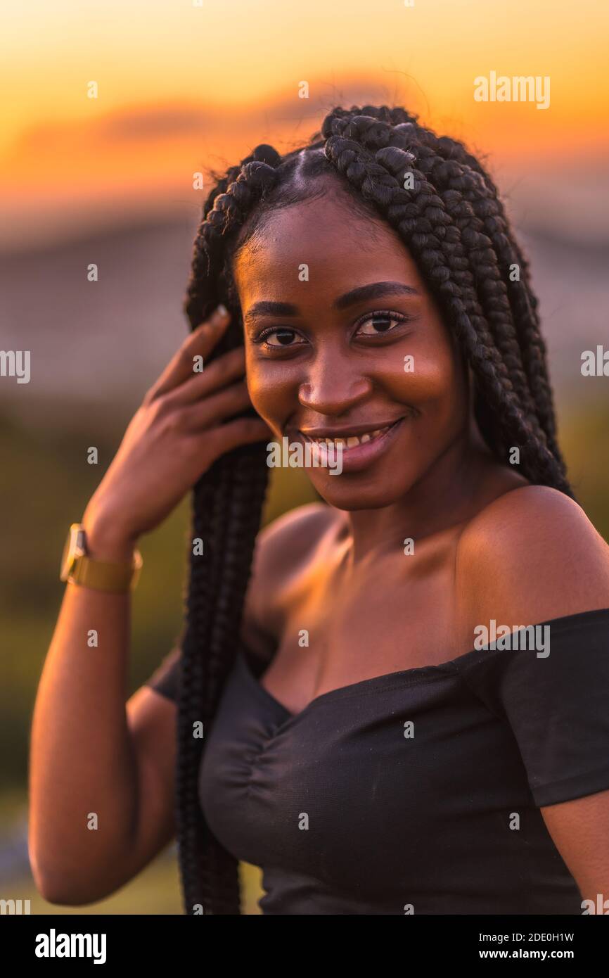 A vertical shot of an African-American woman with long braids posing ...